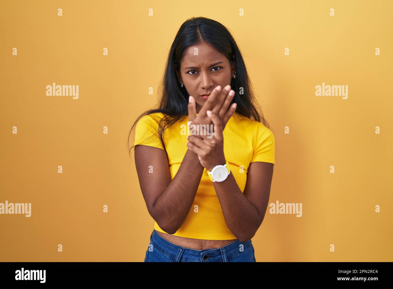 Young indian woman standing over yellow background suffering pain on ...