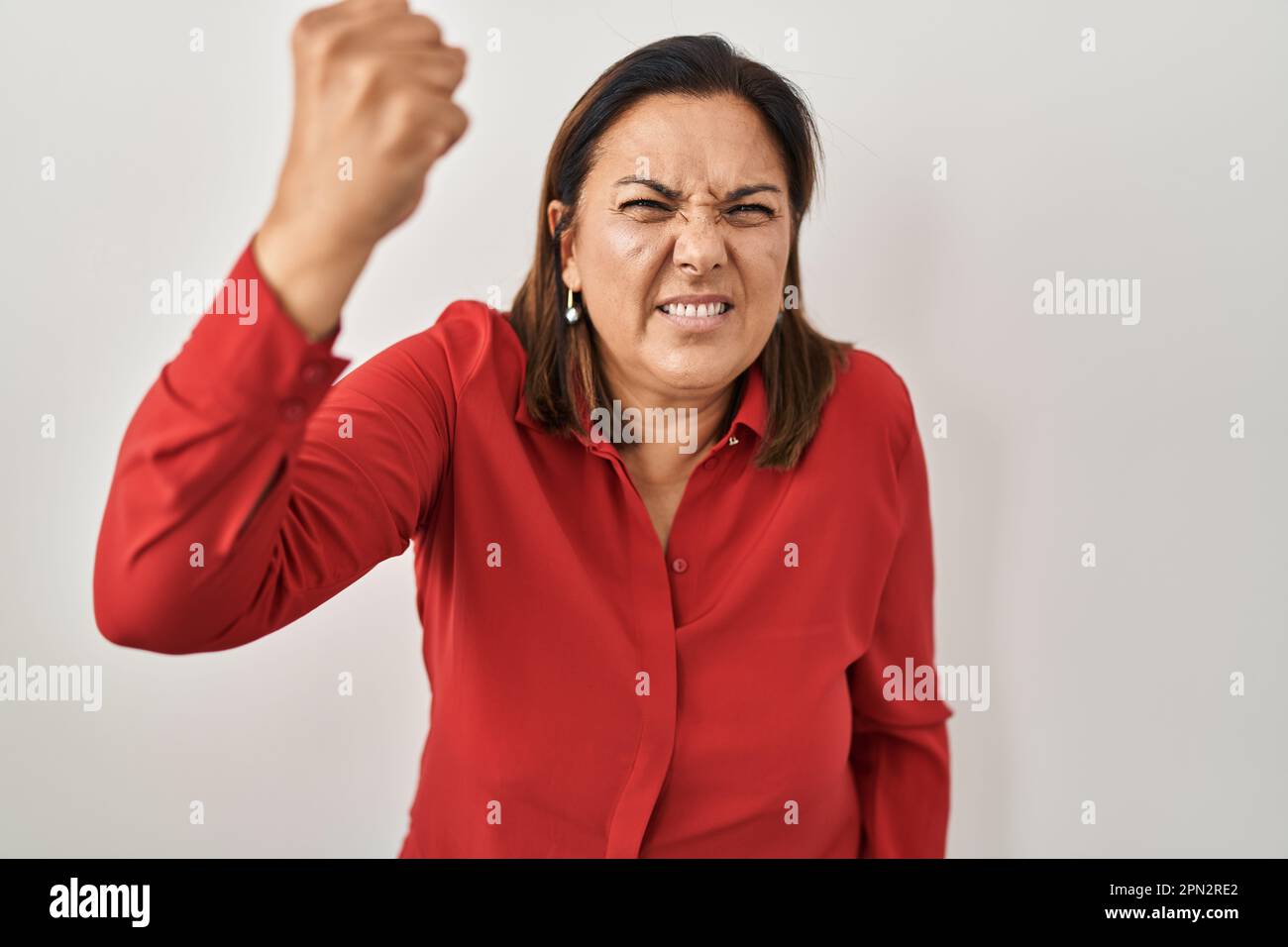 Hispanic mature woman standing over white background angry and mad ...