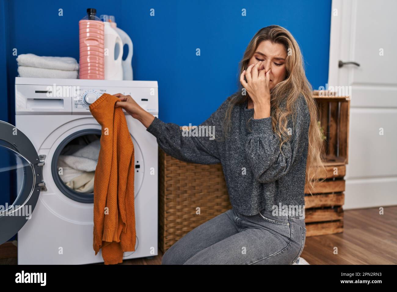 Young blonde woman smelling dirty clothes at laundry room Stock Photo ...