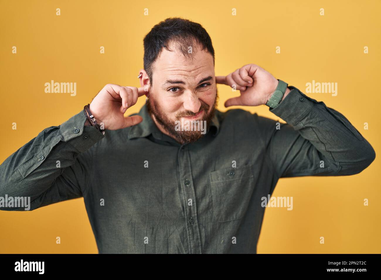 Plus size hispanic man with beard standing over yellow background ...