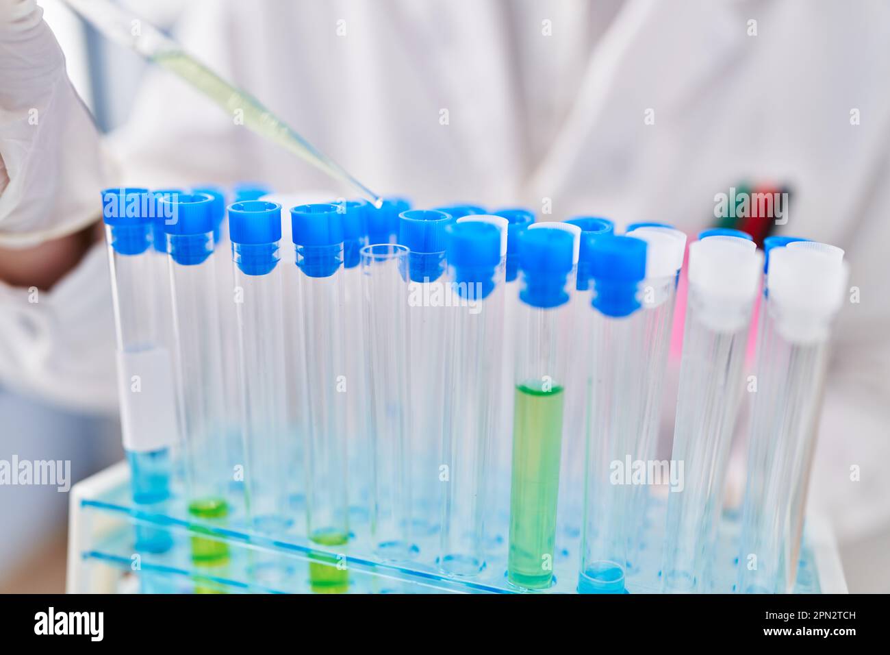 Young woman scientist pouring liquid on test tubes at laboratory Stock ...