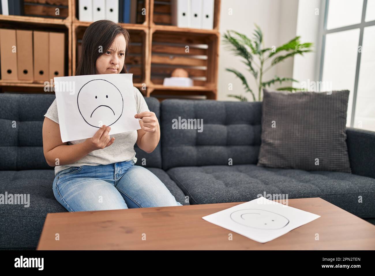 Down syndrome woman patient having psychology session pointing to sad ...