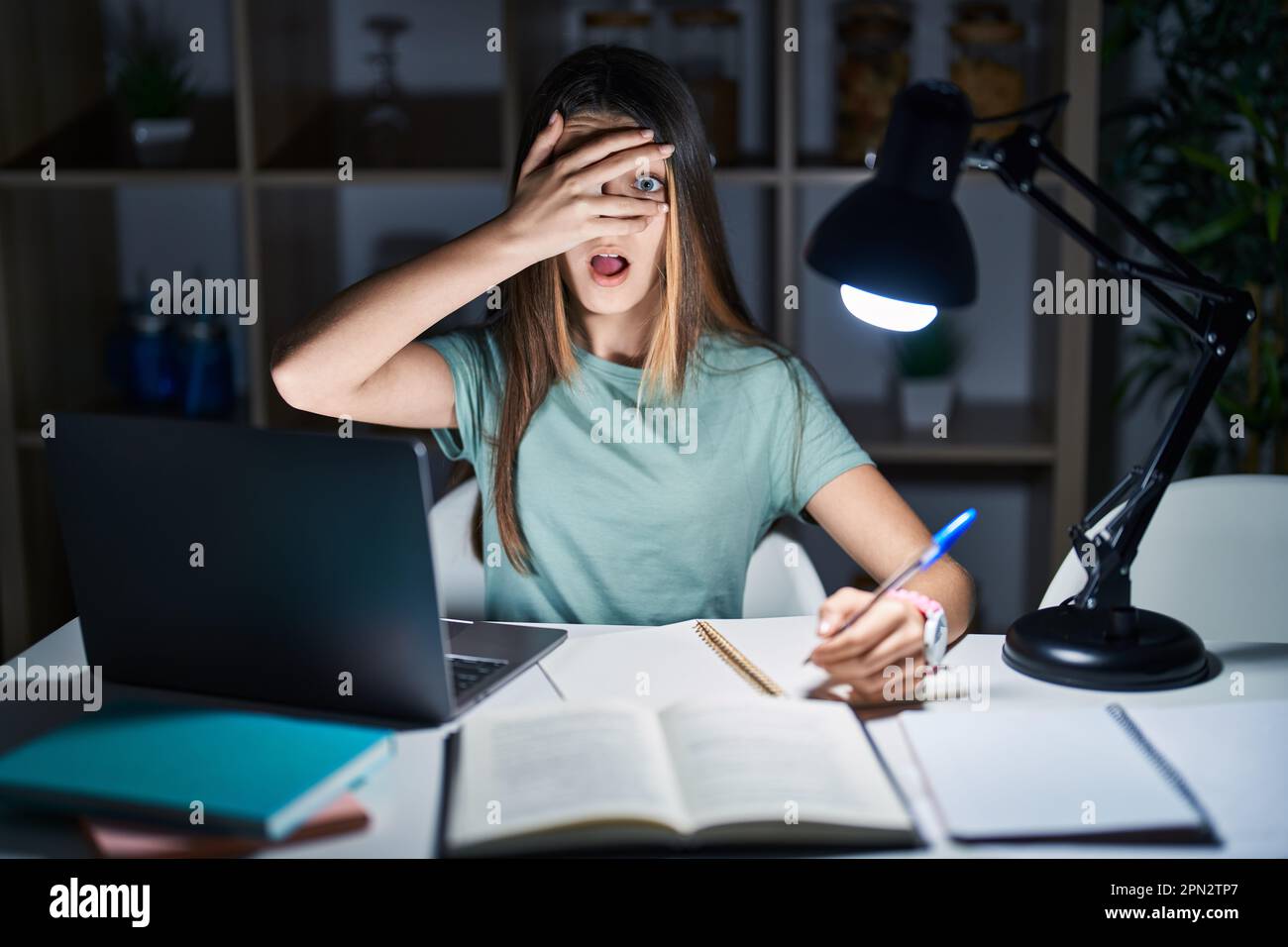 Teenager girl doing homework at home late at night peeking in shock ...