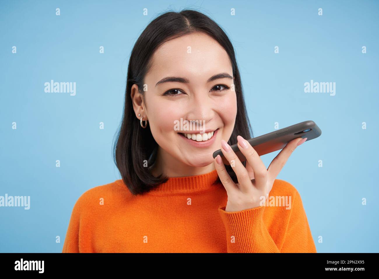 Portrait of asian woman records voice message, talks on speakerphone ...