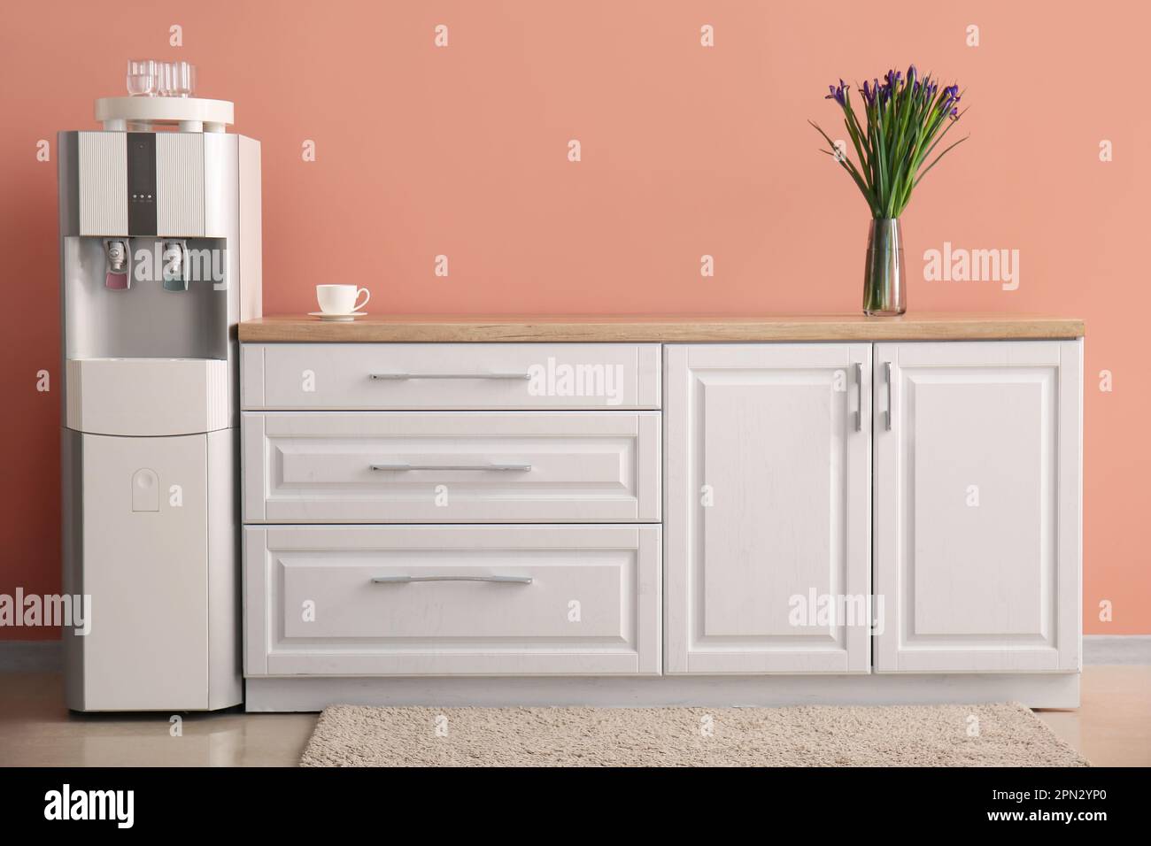 Interior of kitchen with modern water cooler near coral wall Stock ...