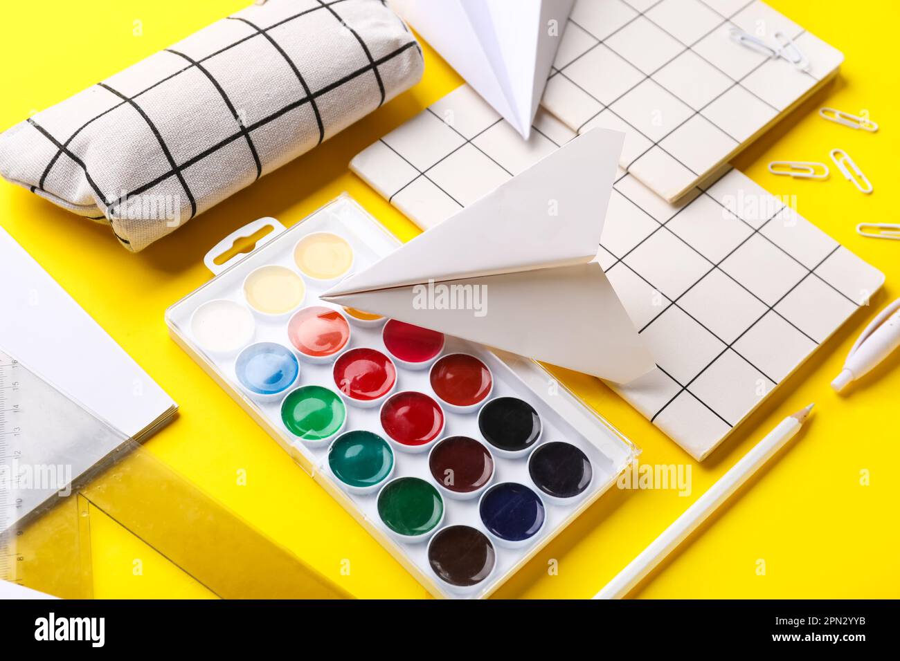 Composition with paints, notebooks and paper planes on yellow ...
