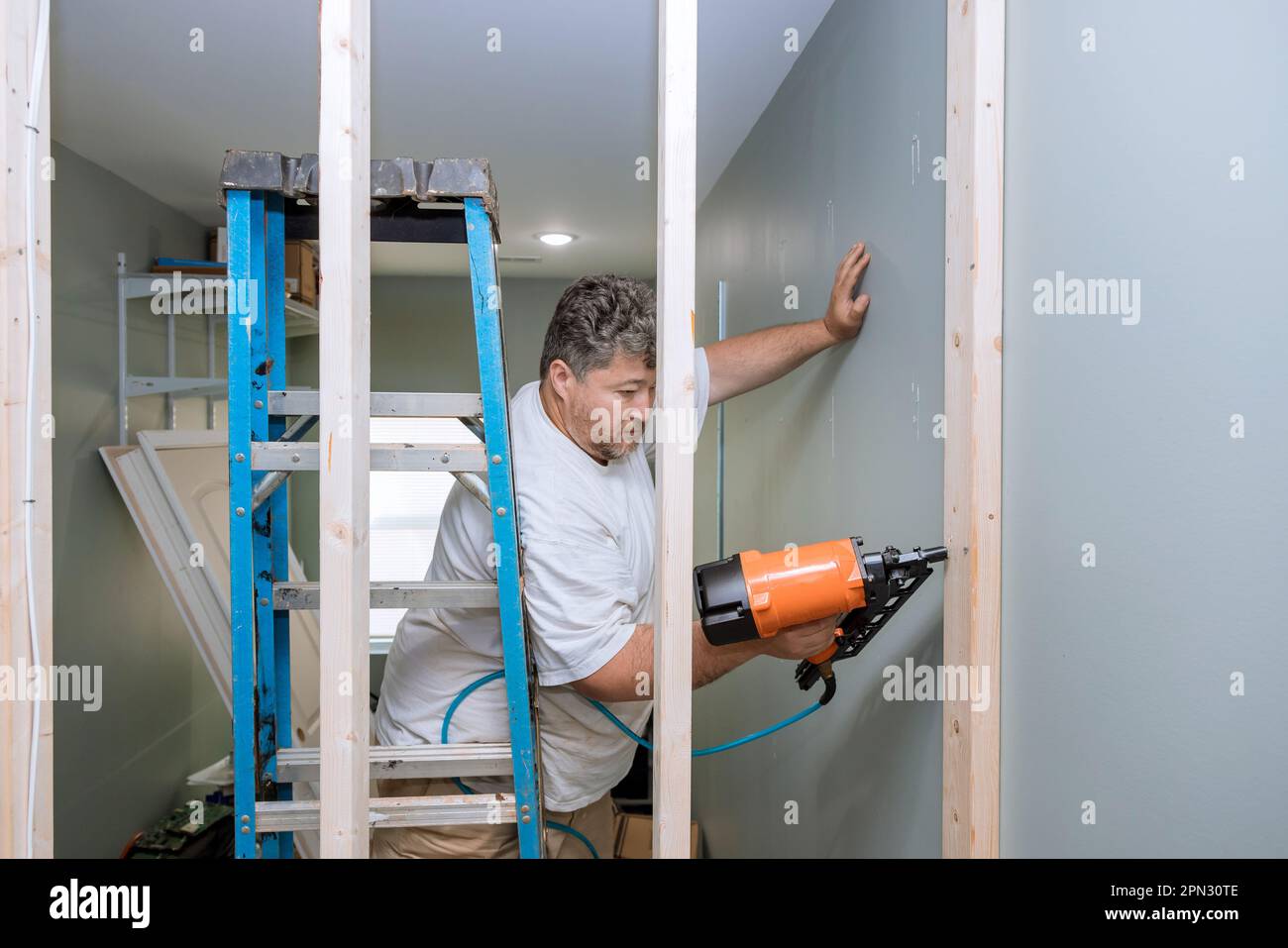 Construction worker uses an air hammer to nail wooden beams housing ...
