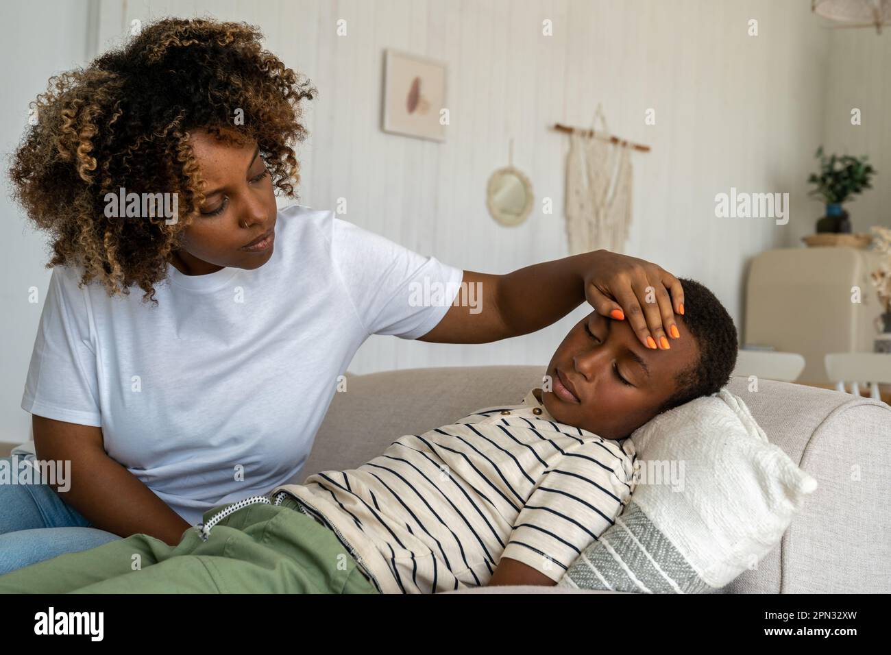 Loving worried African American woman mother taking care of sick child son at home Stock Photo ...