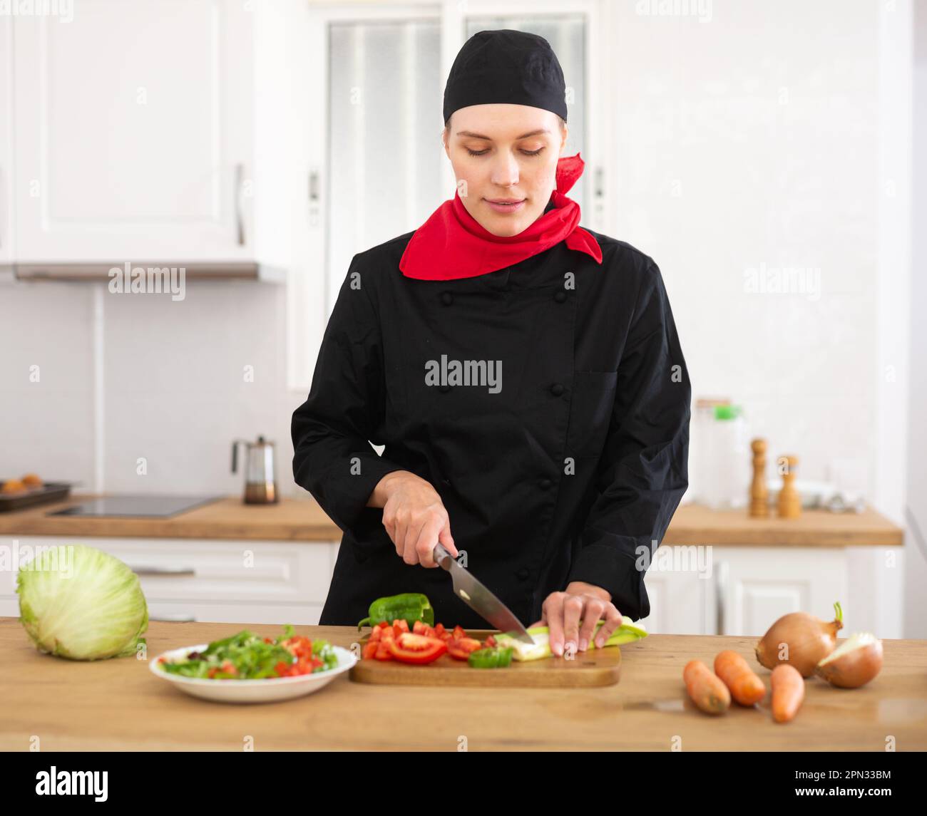 Female cook in black uniform chopping vegetables in kitchen Stock Photo ...