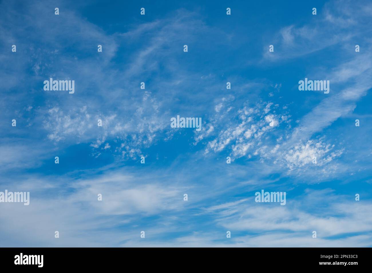 Blue sky with soft, wispy white clouds stretching across, creating a ...
