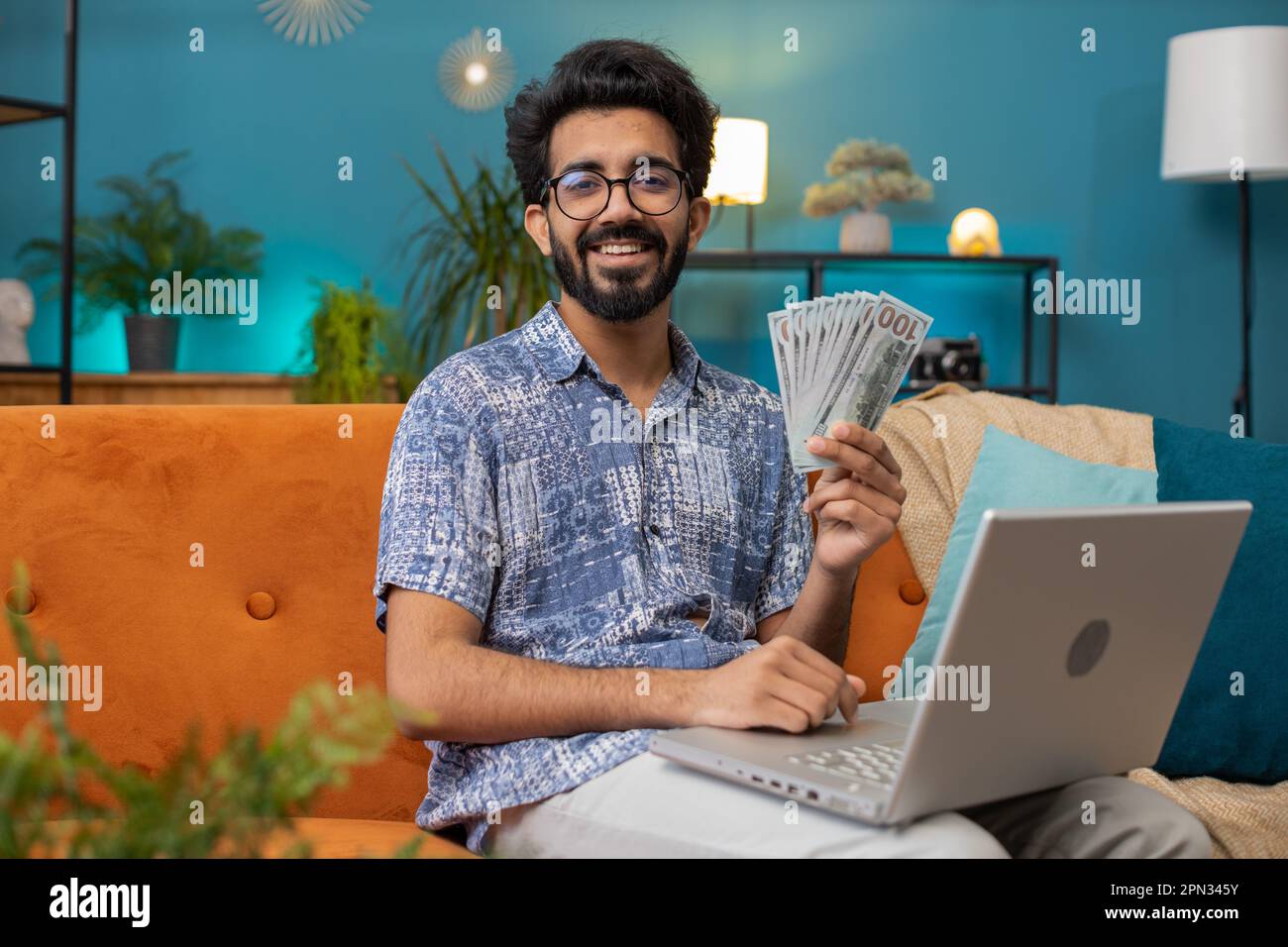 Planning budget. Rich happy indian man counting money cash use laptop ...