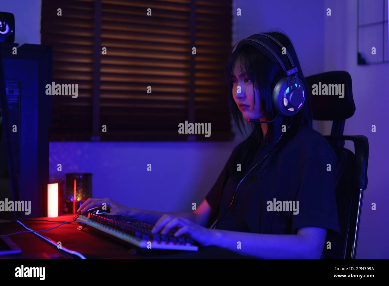 Female cyber hacker gamer in headphone concentrated to playing games or ...