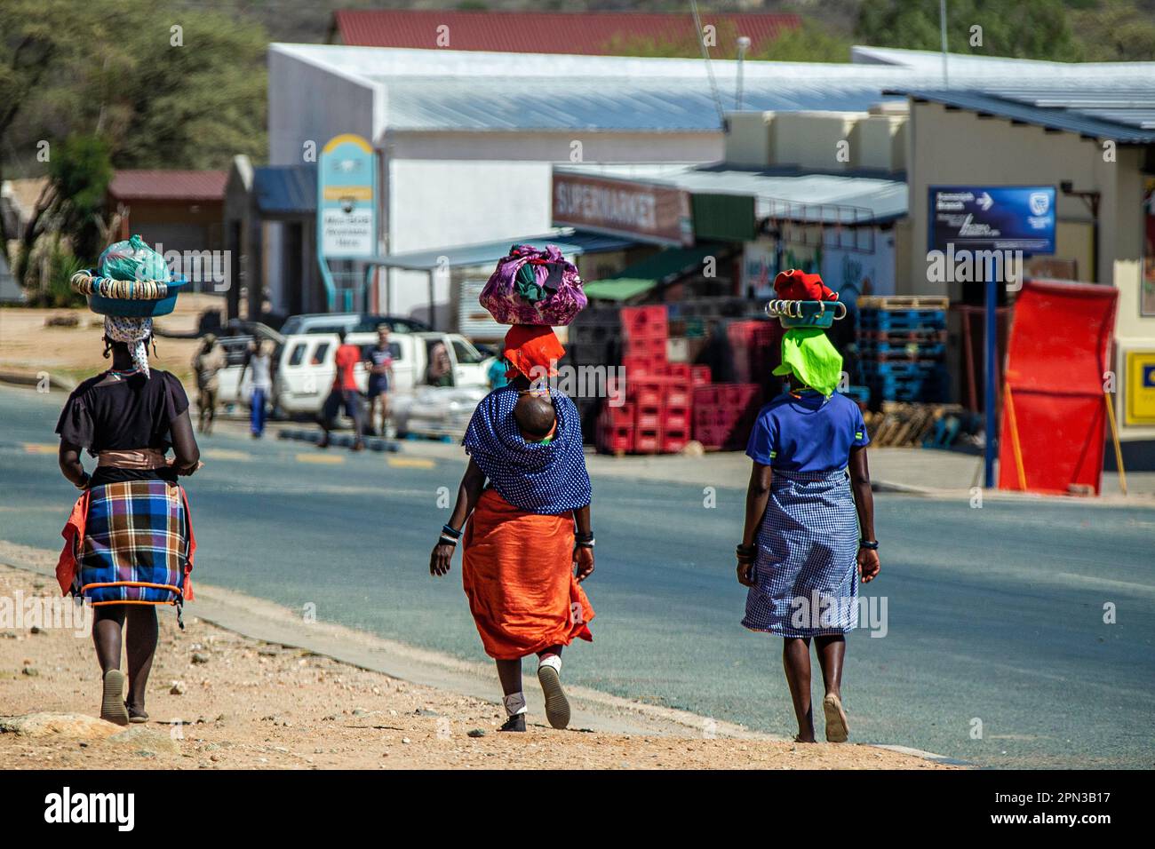 Back view of three ladies in bright, colourful clothes, one with a baby ...
