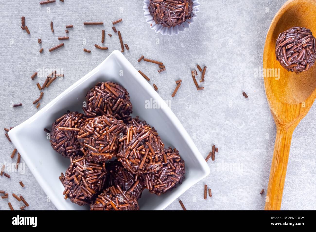 "Brigadeiro" candy in a white form next to others in a white bowl and ...
