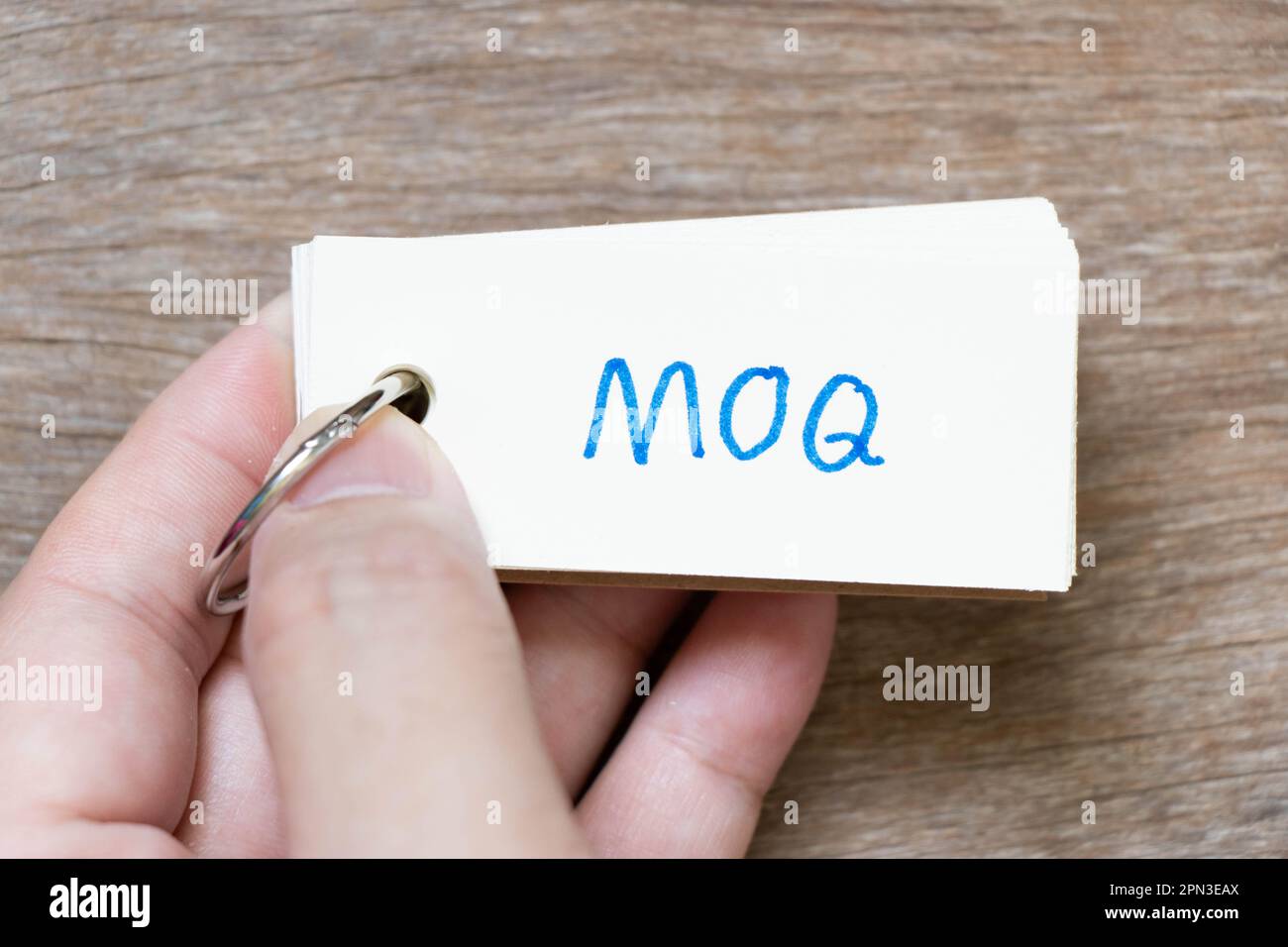 Hand hold flash card with handwriting in word MOQ (Abbreviation of ...