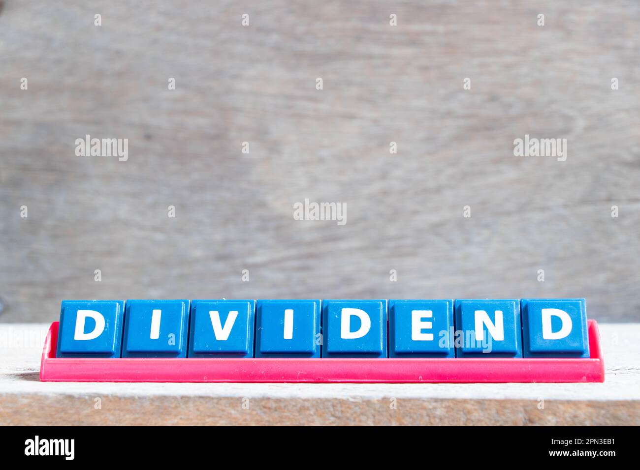 Tile alphabet letter with word dividend in red color rack on wood ...
