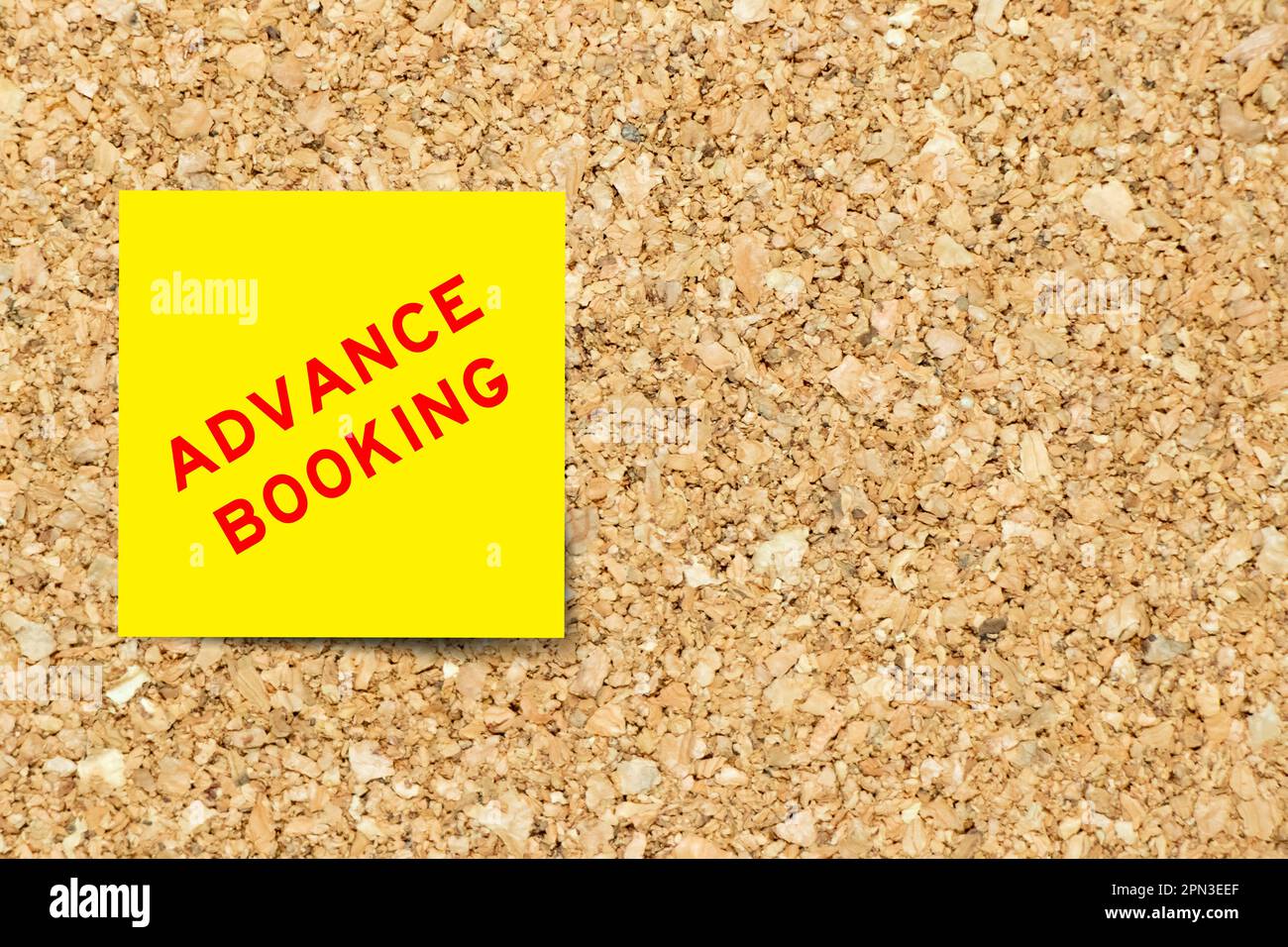 Yellow note paper with word advance booking on cork board background ...