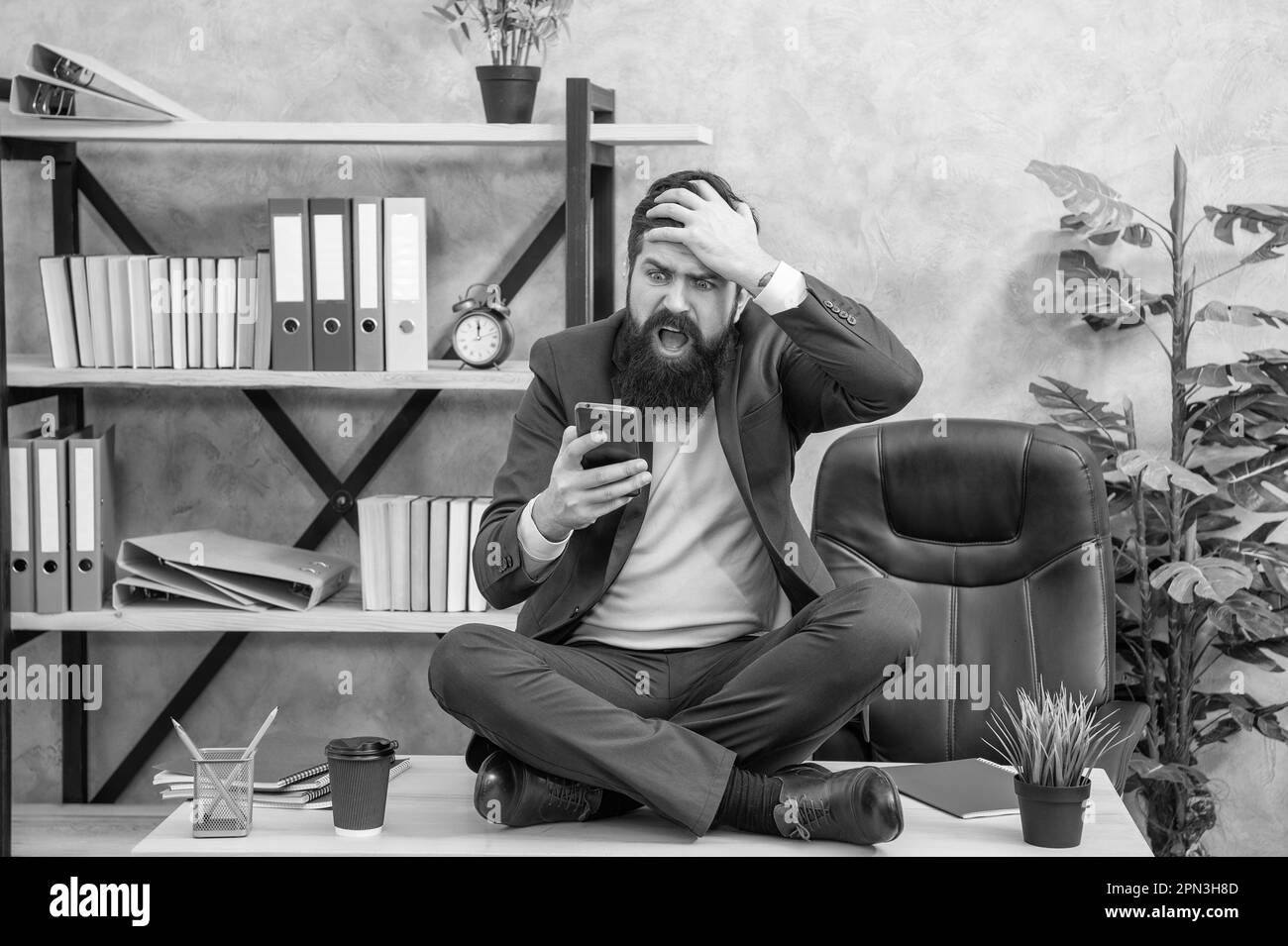 Stressed manager reading sms in mobile phone clutching head and sitting ...