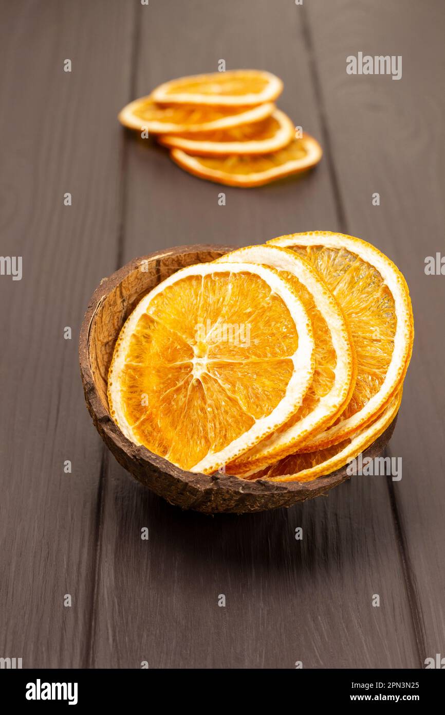 Orange chips in a coconut shell. Slices of dried orange on the table ...