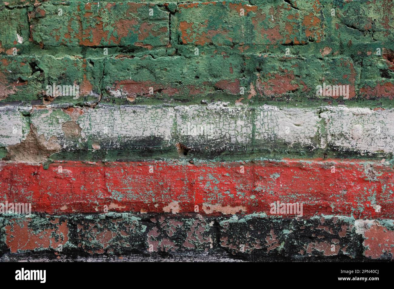 Weathered and painted brick wall with red, green and black stripes ...