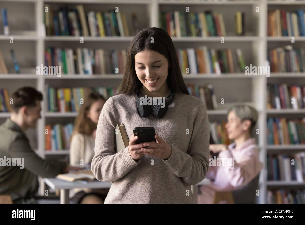 Student girl standing in college library use smart phone Stock Photo ...