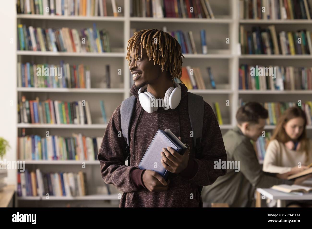 Young African guy pose in library with schoolmates on background Stock ...