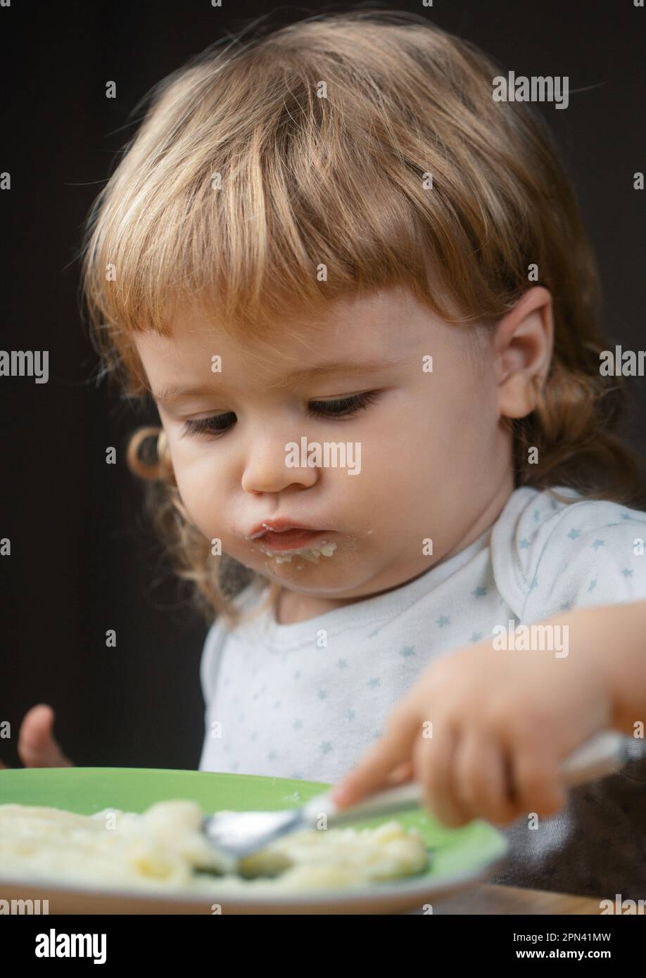 Kid baby with a spoon and a plate in the kitchen at home Stock Photo ...
