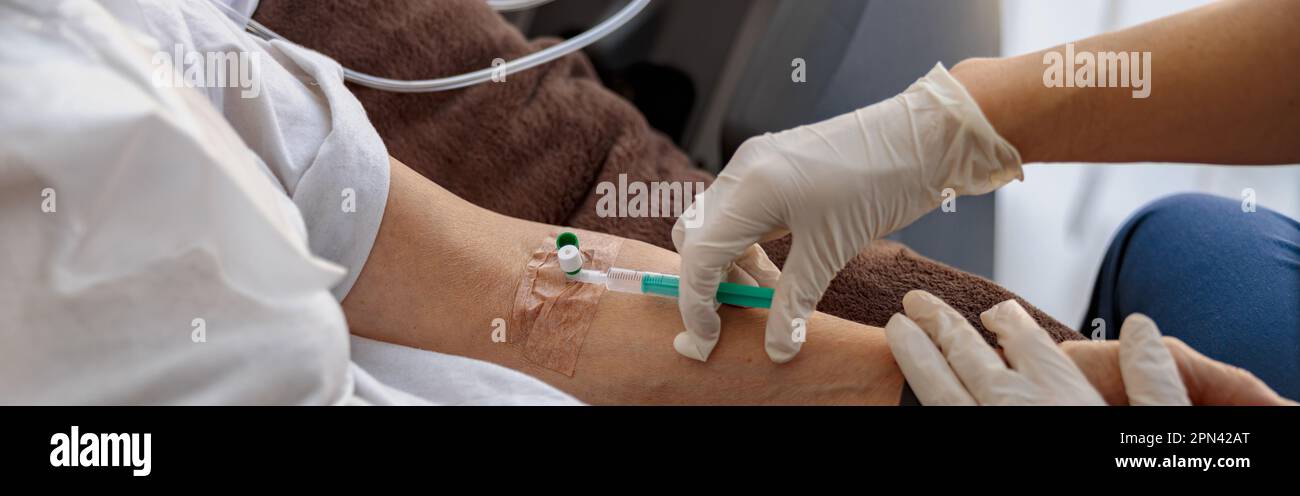 Nurse putting a drip in the arm of her patient in modern medical clinic ...