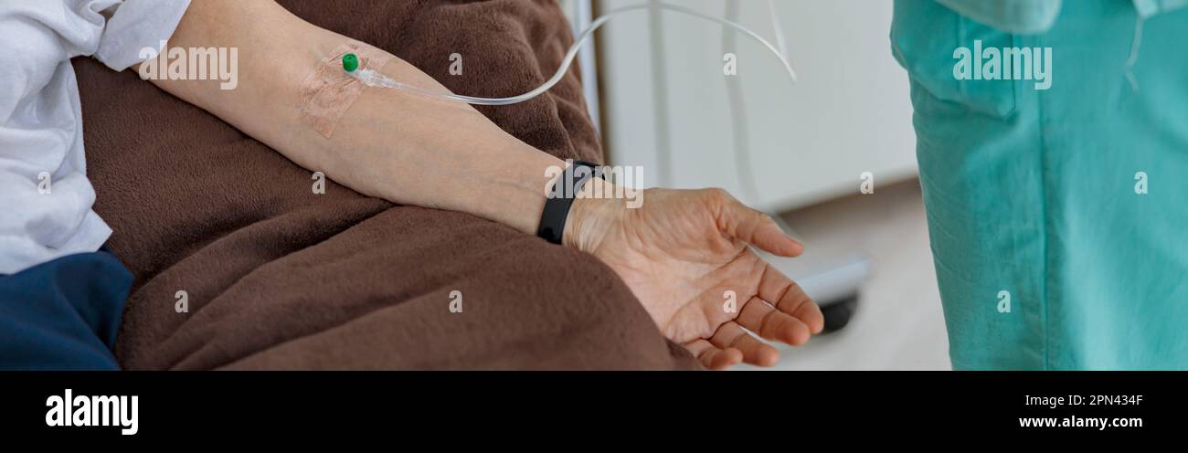 Nurse putting a drip in the arm of her patient in modern medical clinic ...