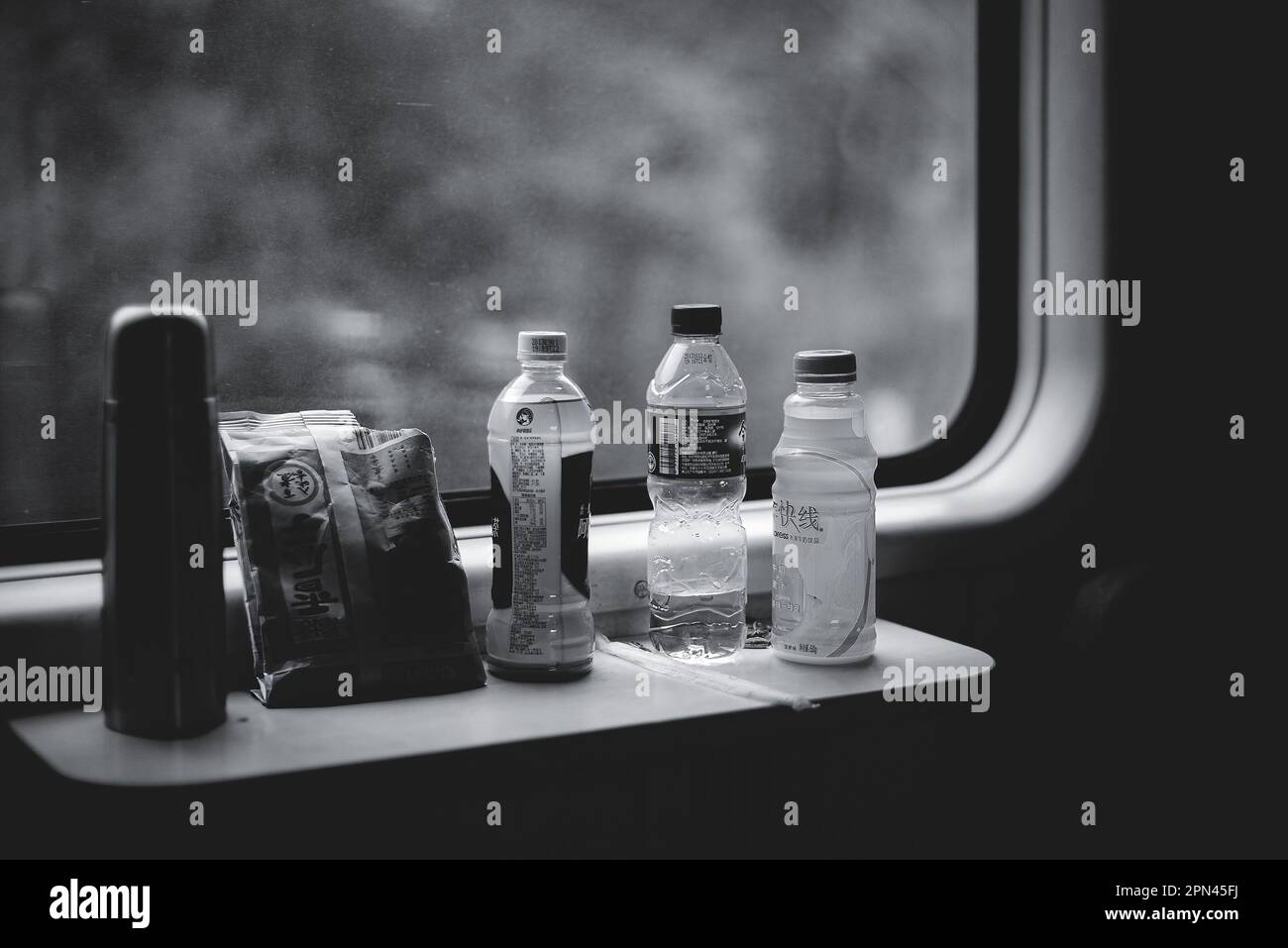 There are many empty cold drink bottles on the windowsill of the train ...
