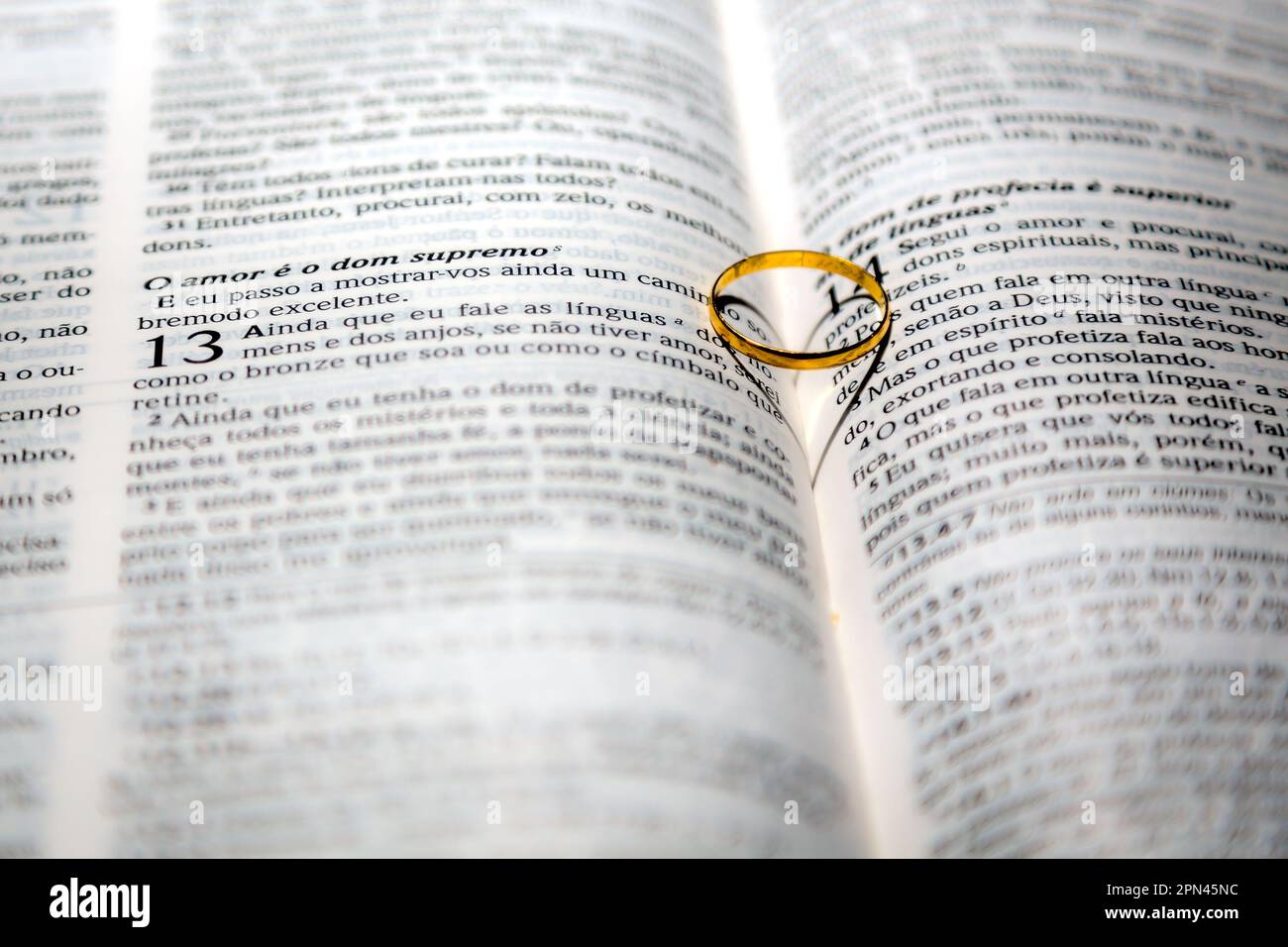 A golden wedding ring placed on top of a stack of open book pages ...