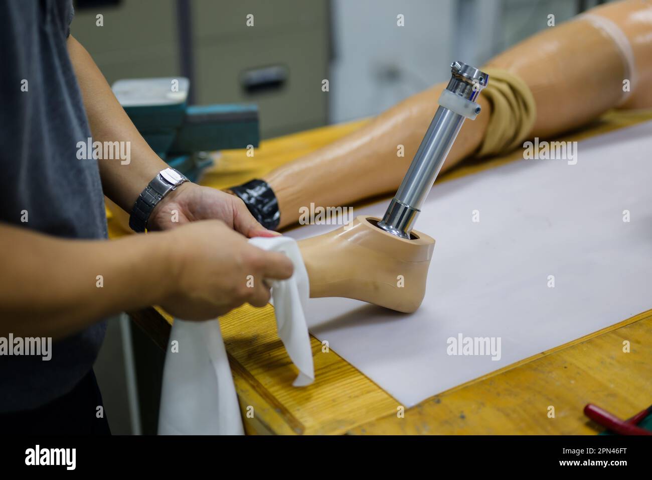 Male worker assembling parts of artificial leg in prosthetic workshop ...