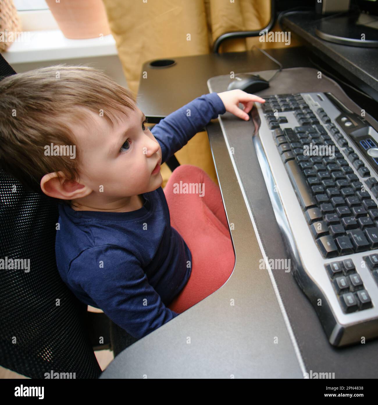 Toddler baby works on a computer with a keyboard and mouse. Happy child ...