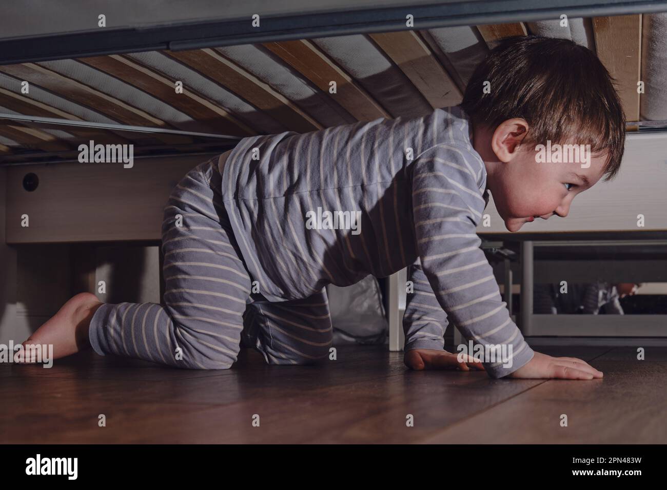 Toddler baby crawls and hides under the bed. Child climbed under the ...