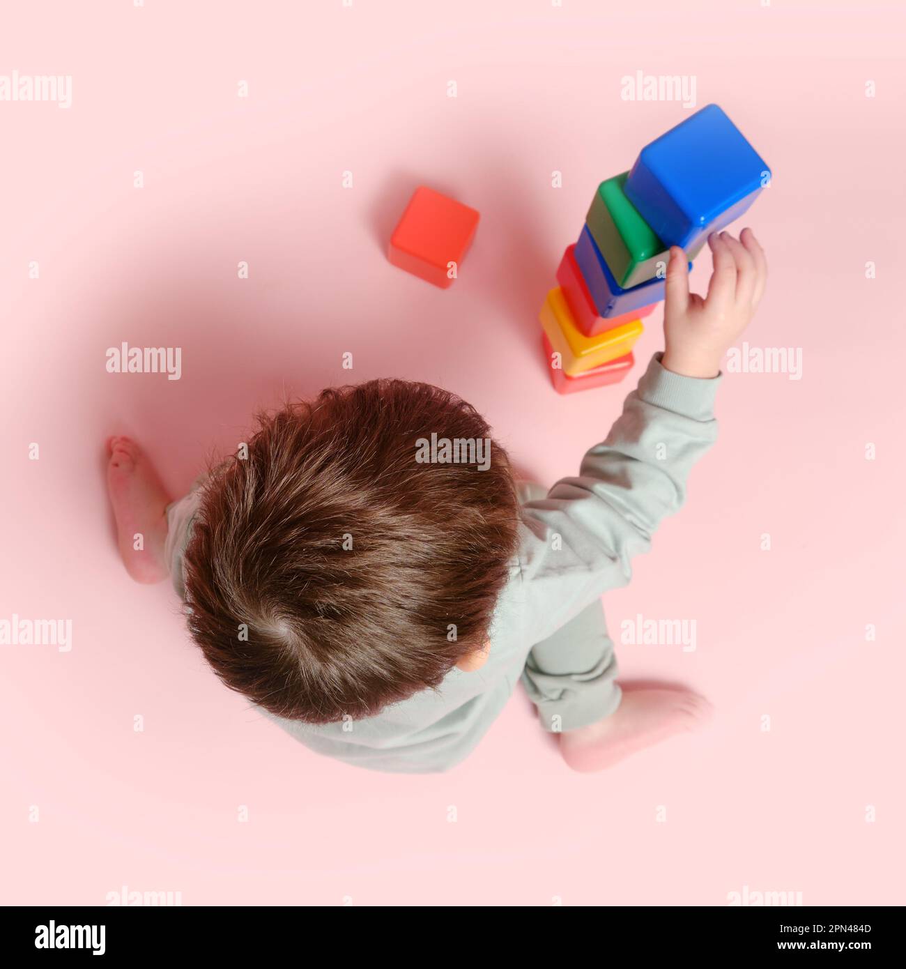 Happy toddler baby plays with cubes on studio pink background. Child ...