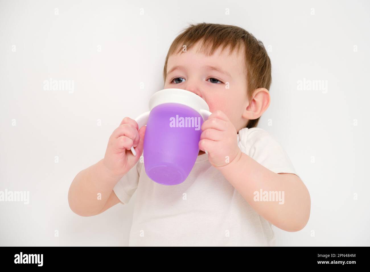 Happy baby drinks water from cup on studio white background. Resting ...
