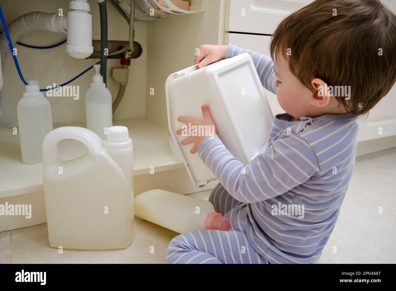 A child is playing with chemical cleaning products under the sink in ...