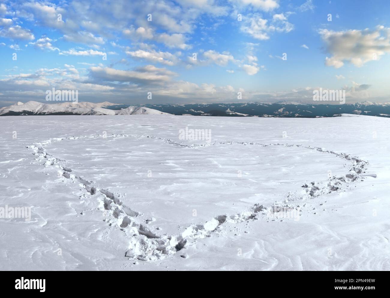 Human footprint form the heart shape on snow-covered mountainside ...