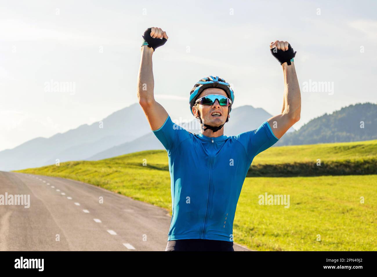 Male athlete professional racing cyclist riding a bike with arms raised ...