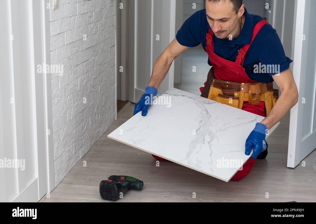 Industrial tiler builder worker installing floor tile at repair ...