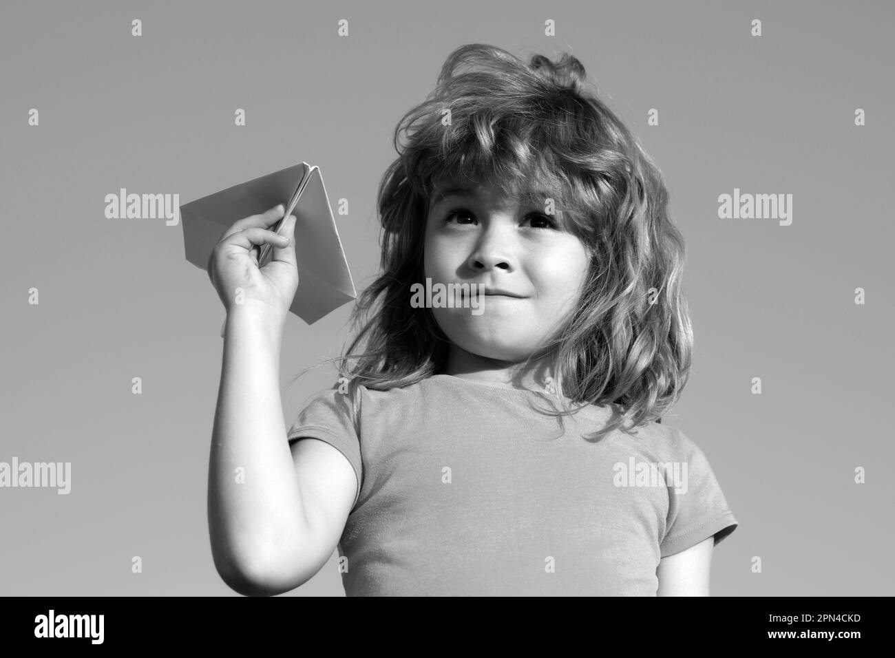Fun little boy dreams of aviator while playing a paper plane at sky ...