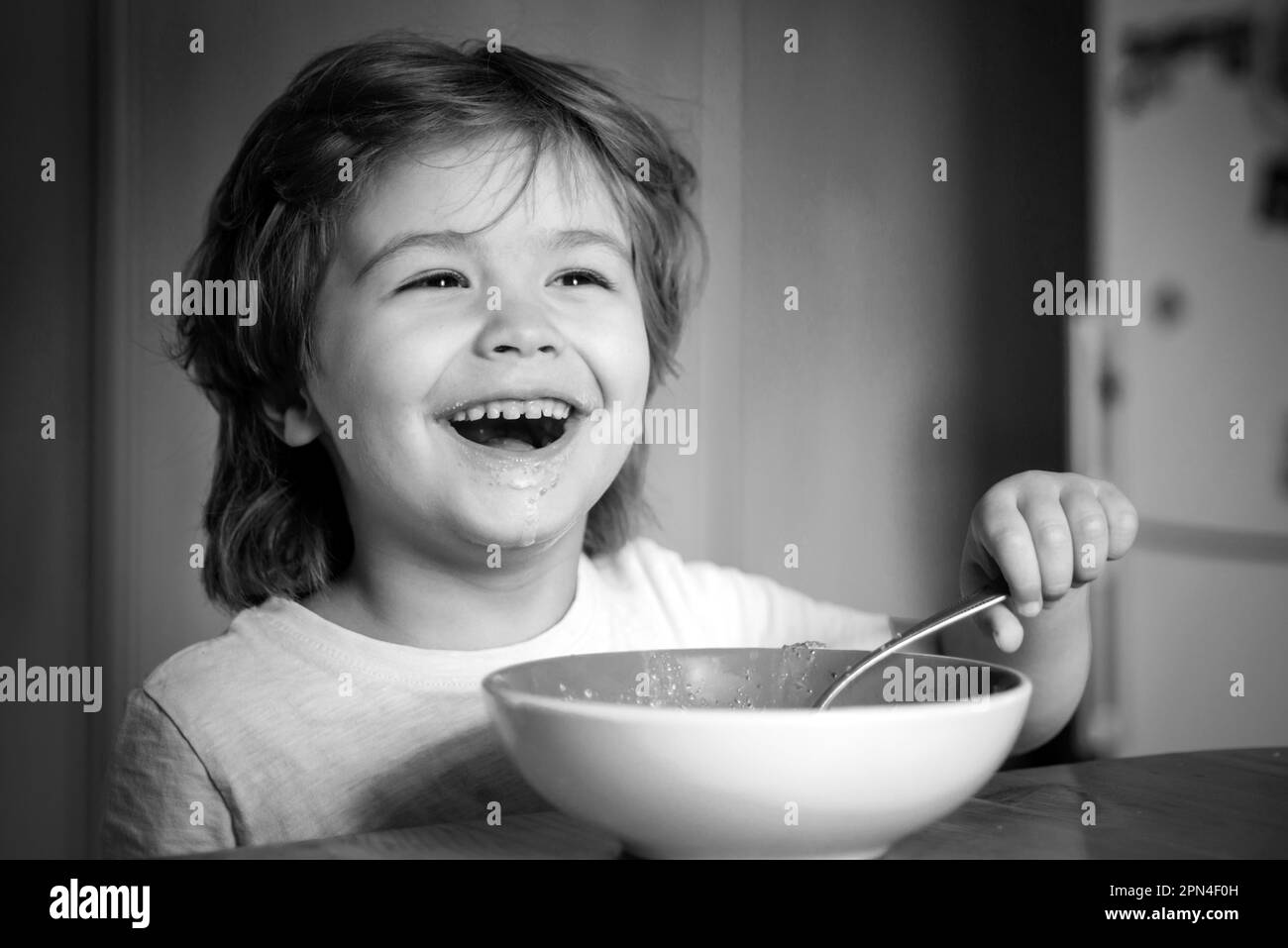 Kid eating. Little boy having breakfast in the kitchen. Smiling happy ...