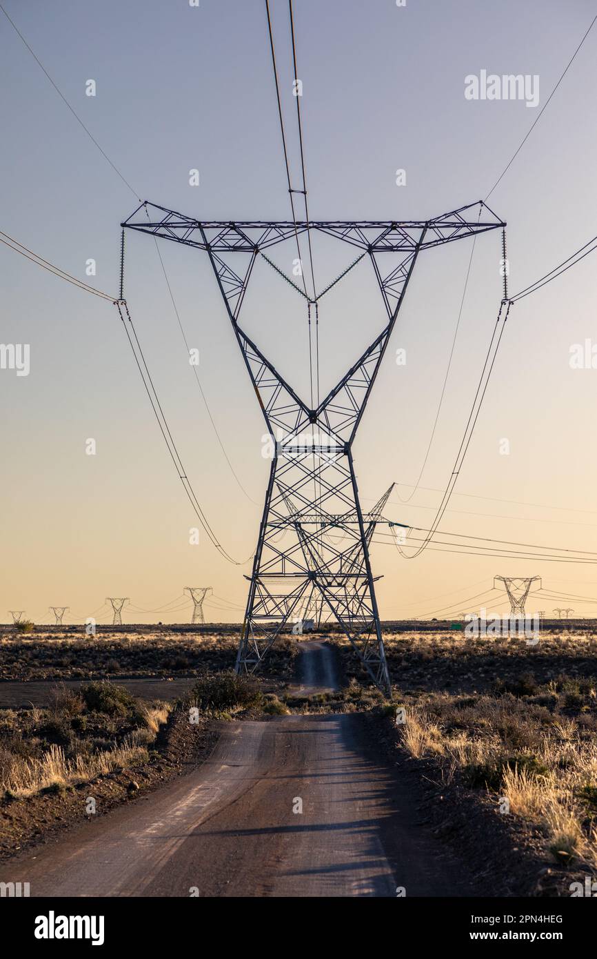 Electricity transmission pylon as dusk with a gravel access road ...