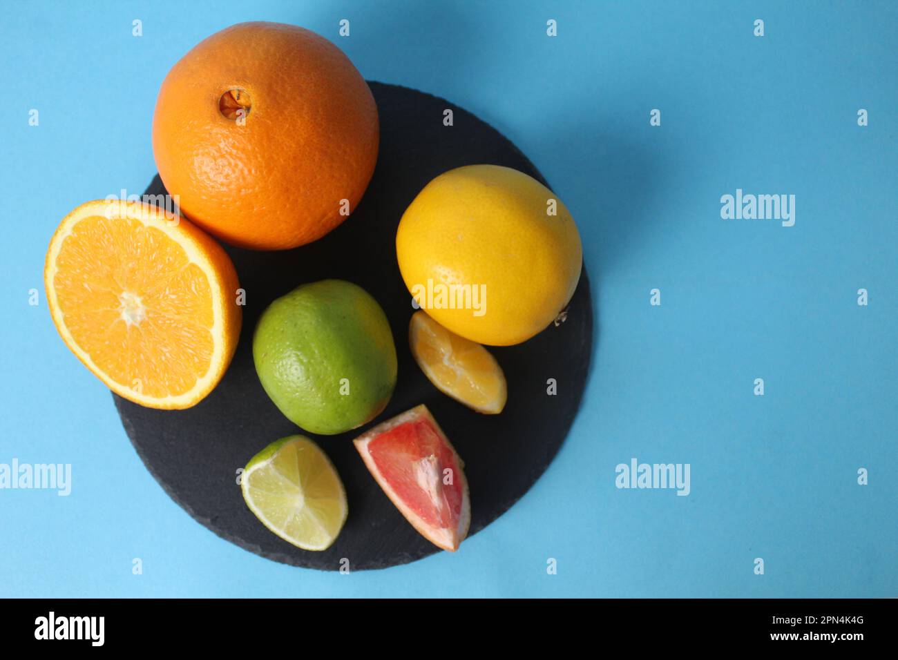 Citrus fruits, orange, lemon, grapefruit, lime lie on a black tray on a ...