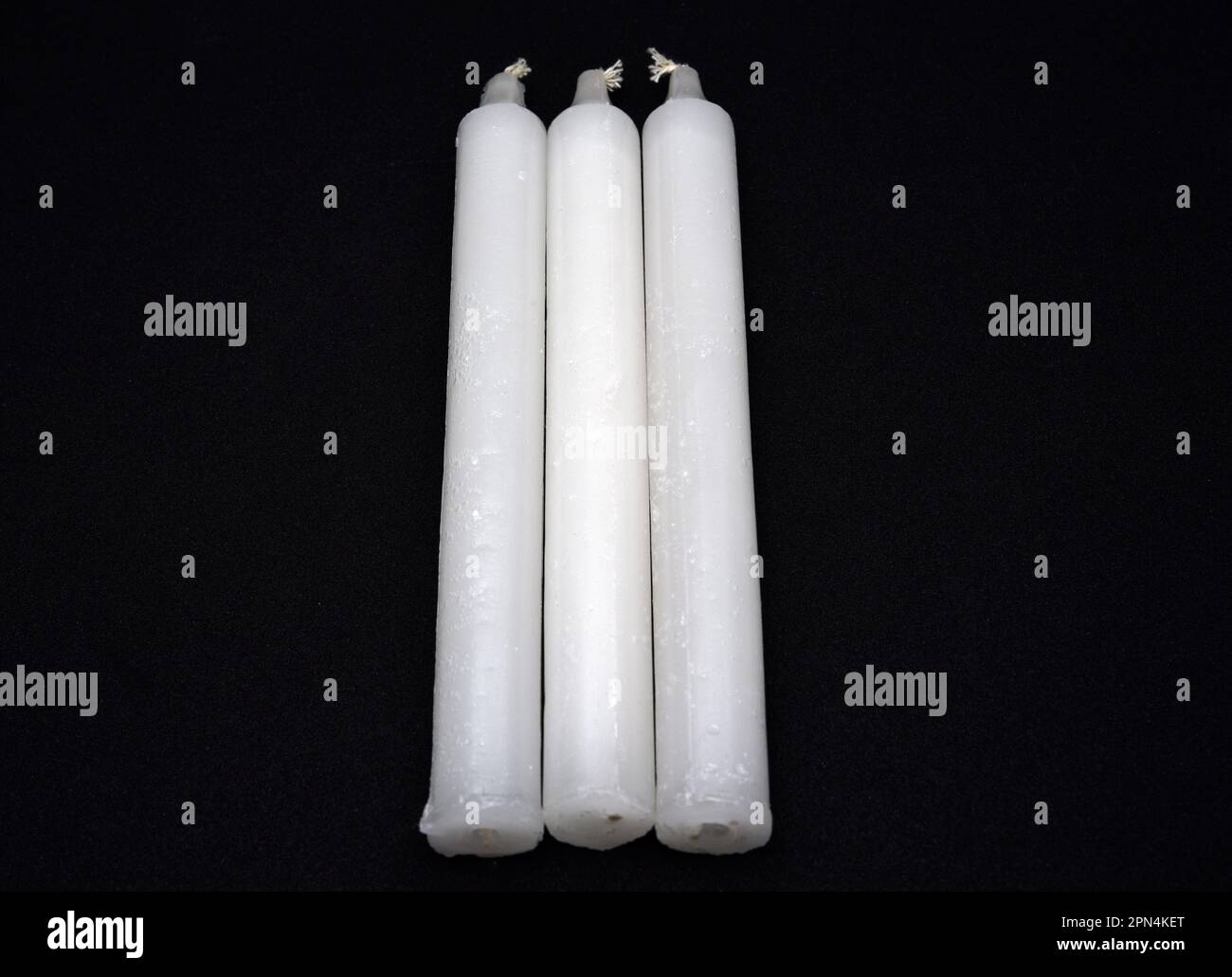 White paraffin candles on a black background. Household candles in a ...