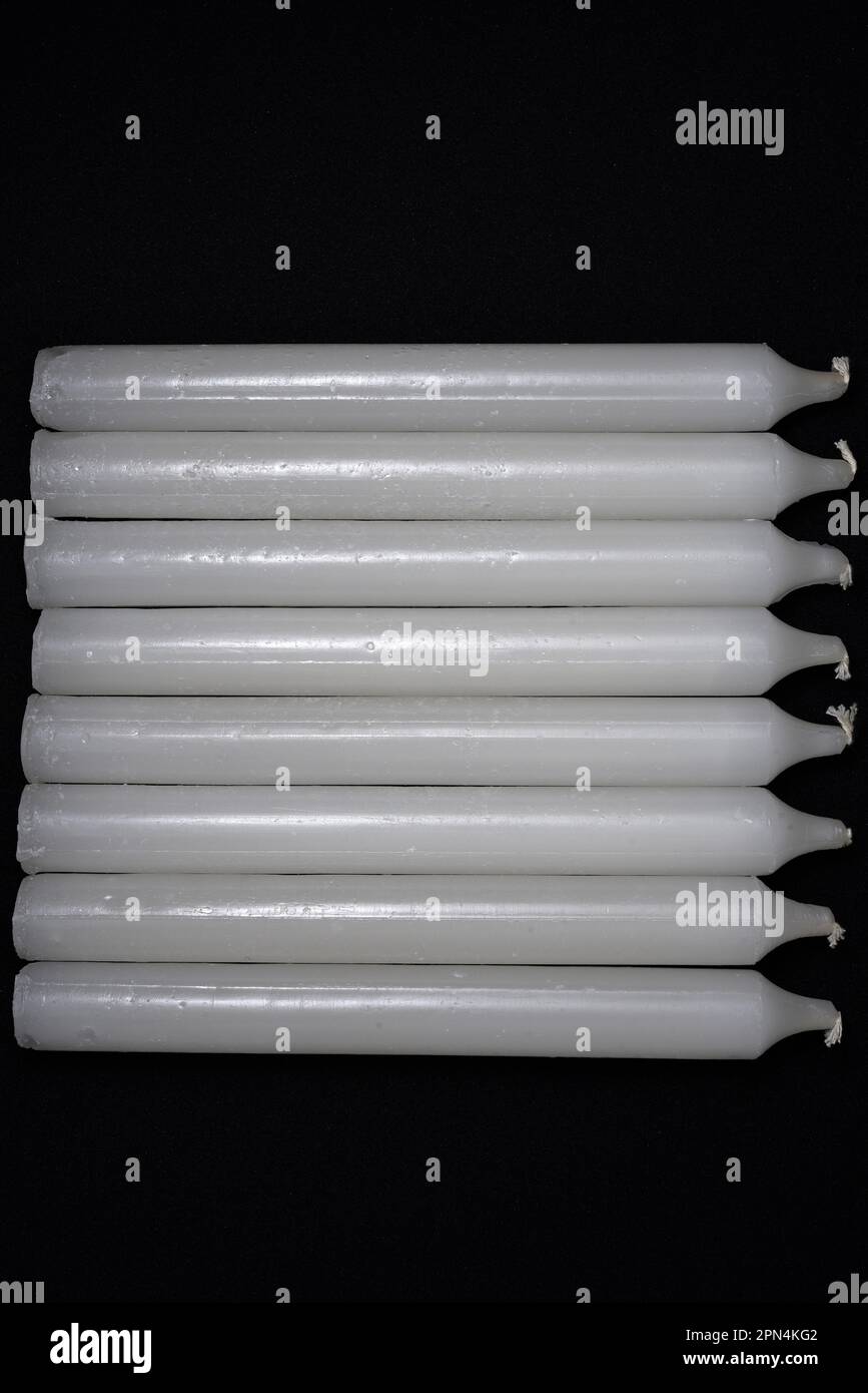 White paraffin candles on a black background. Household candles in a ...