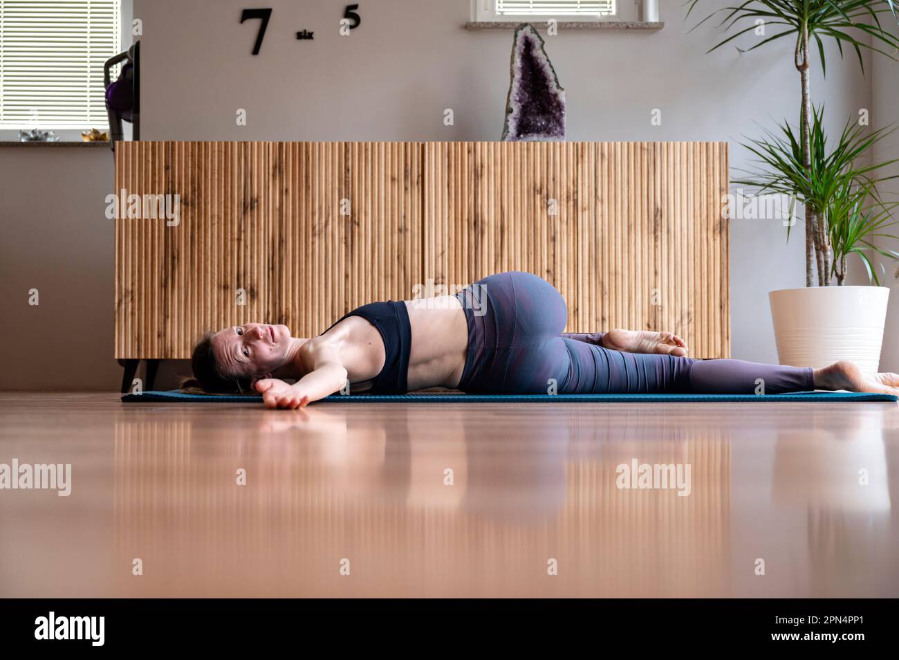 Young woman lying on her back after a home workout routine. Stretching ...