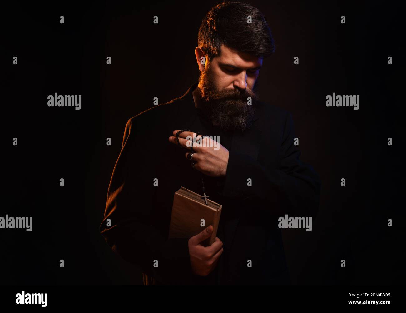 Praying hands priest portrait of male pastor. Man in suit with a Bible ...