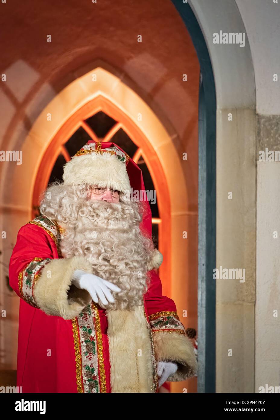 Traditional Father Christmas character outside a brightly lit festive ...
