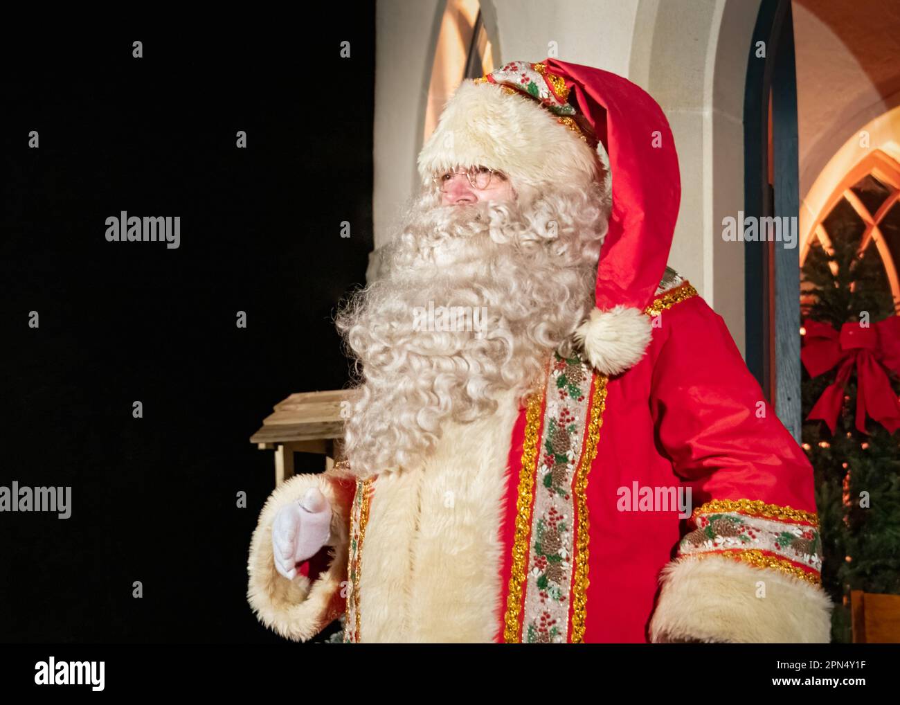 Traditional Father Christmas character outside a brightly lit festive ...